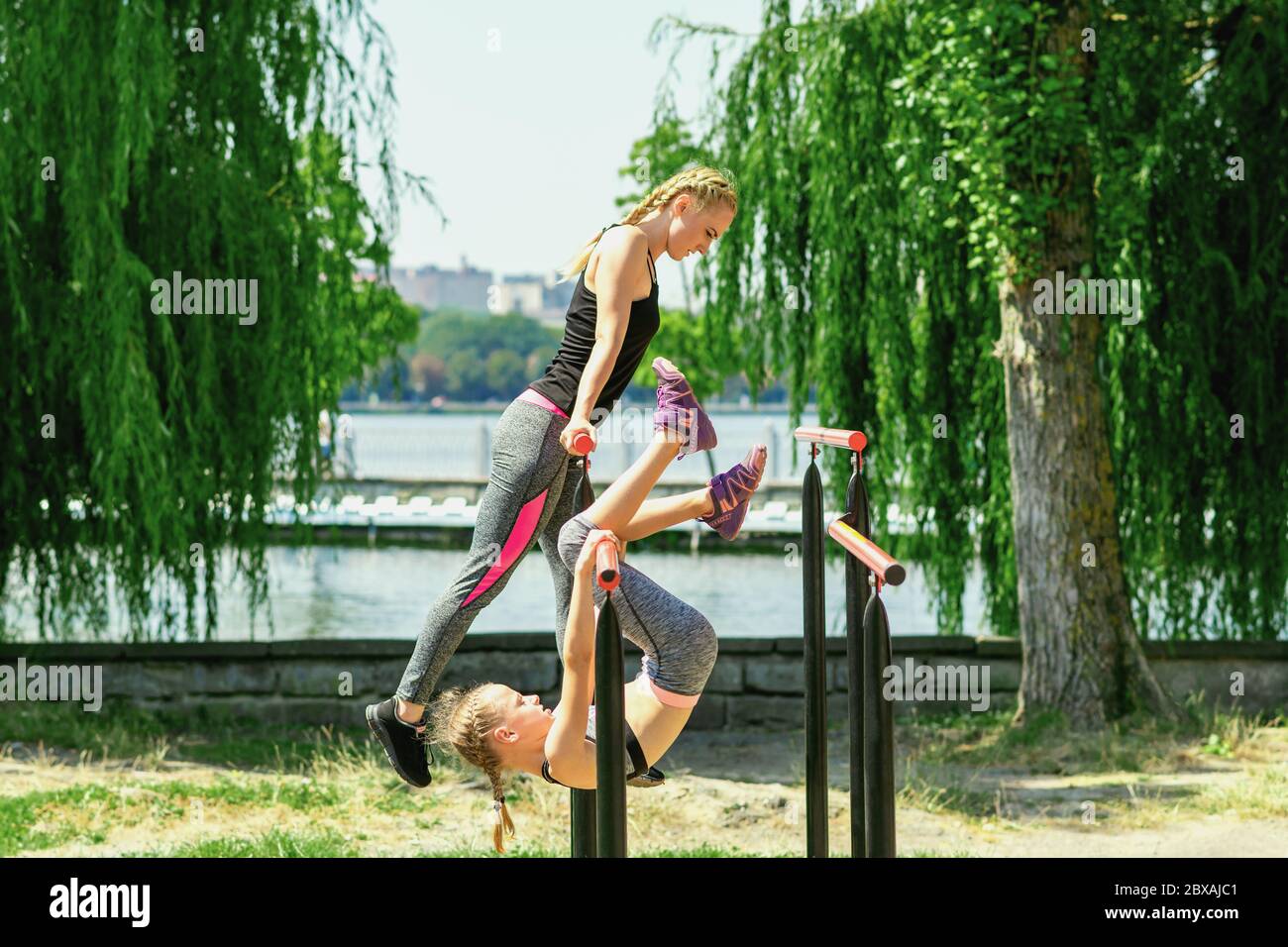 Mother and daughter are training on horizontal bar doing acrobatic ...