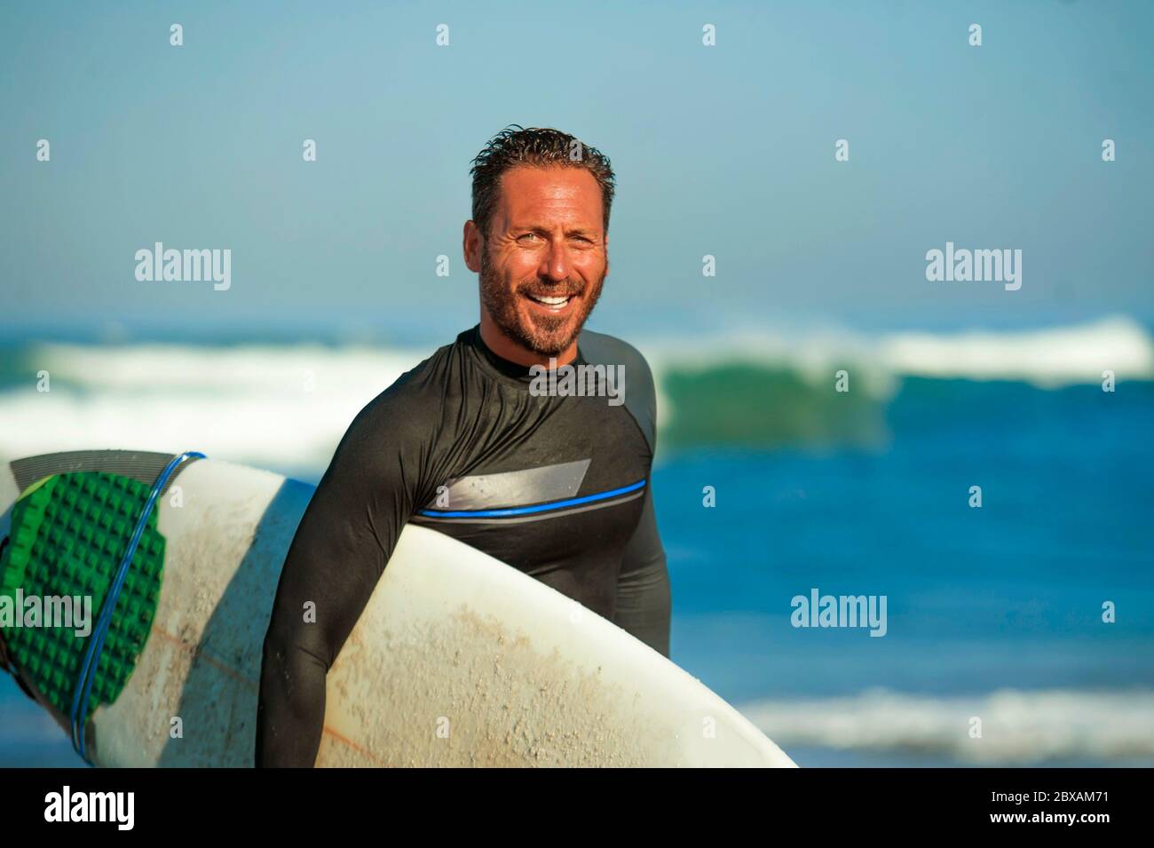 lifestyle beach portrait of handsome and attractive surfer man in ...