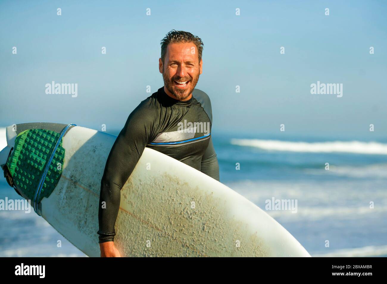 lifestyle beach portrait of handsome and attractive surfer man in ...