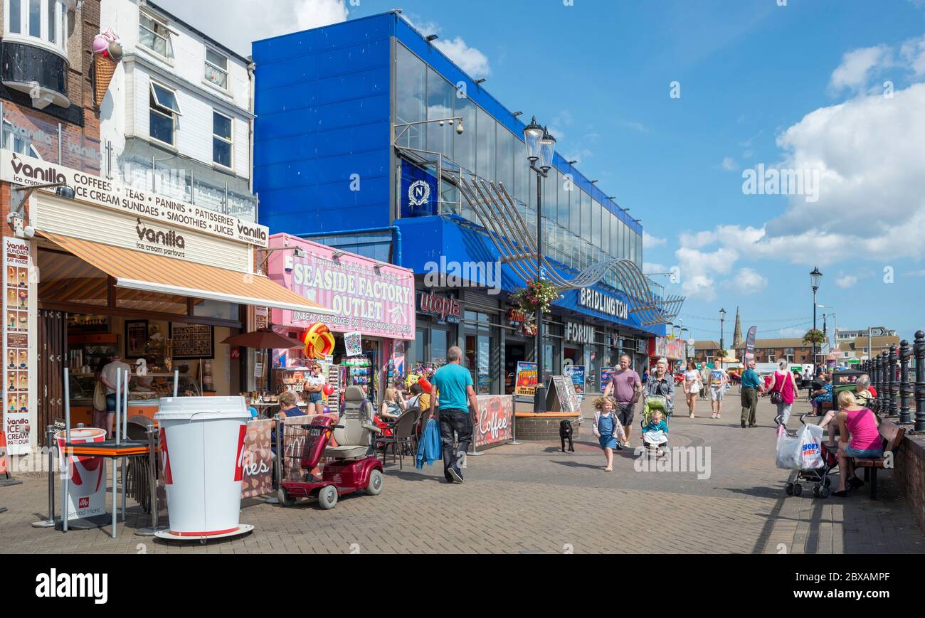 People walking past shops and an amusement arcade on the promenade at ...