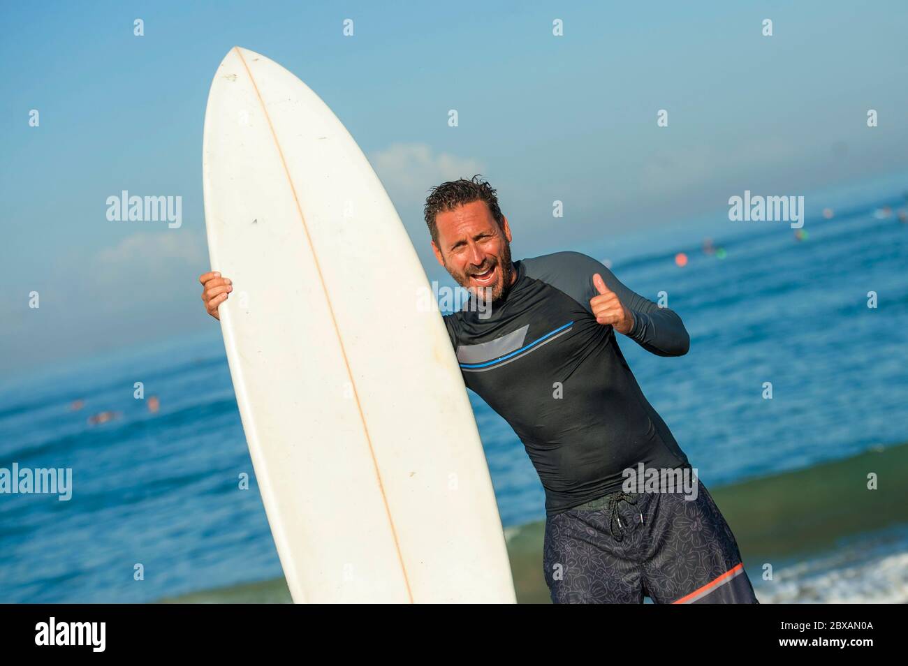 lifestyle beach portrait of handsome and attractive surfer man in ...