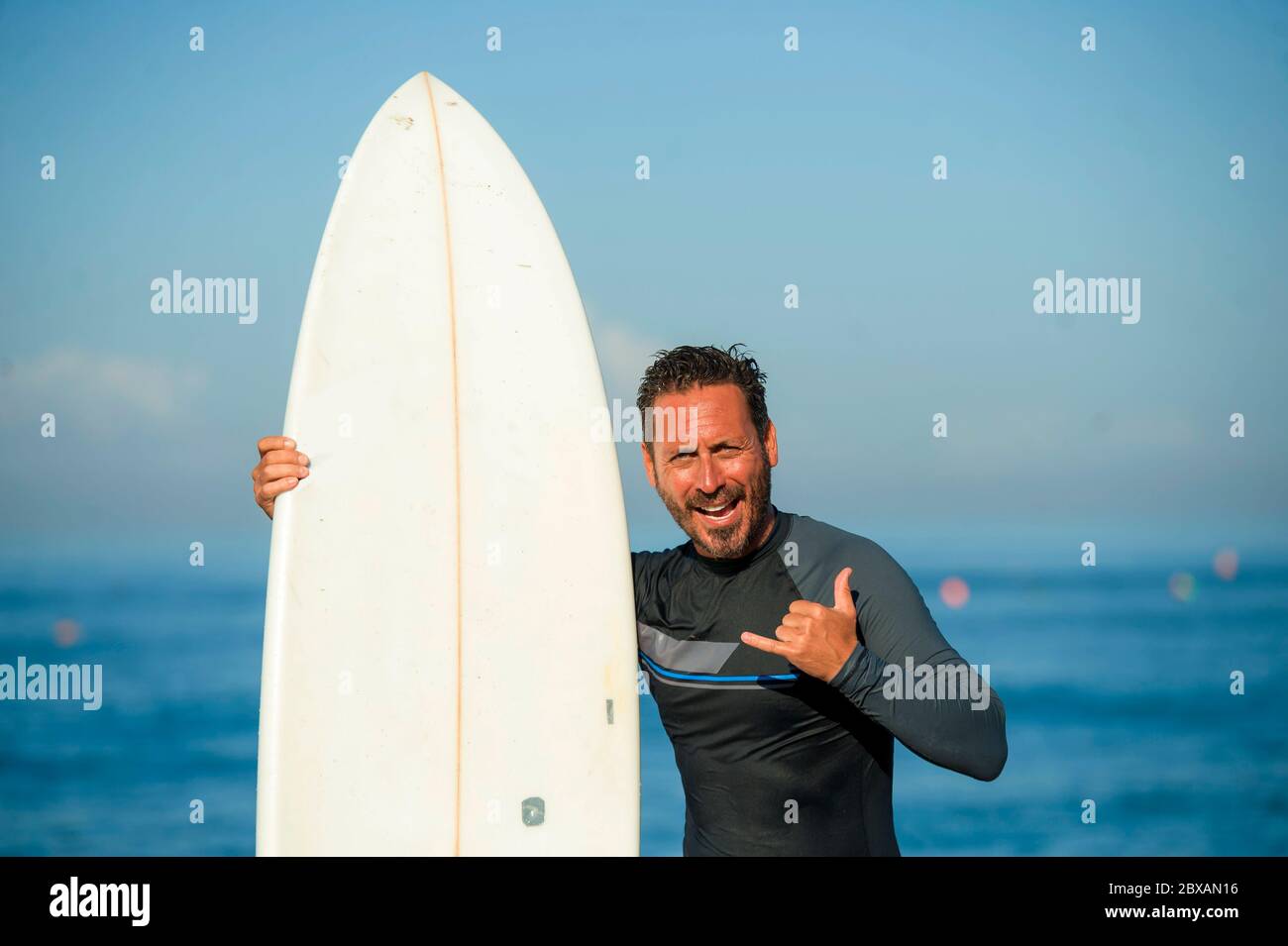 lifestyle beach portrait of handsome and attractive surfer man in ...
