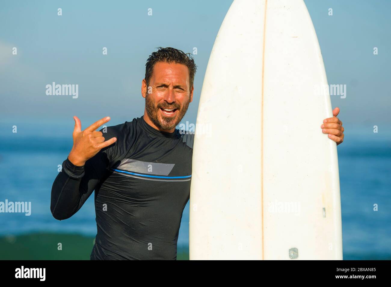 lifestyle beach portrait of handsome and attractive surfer man in ...