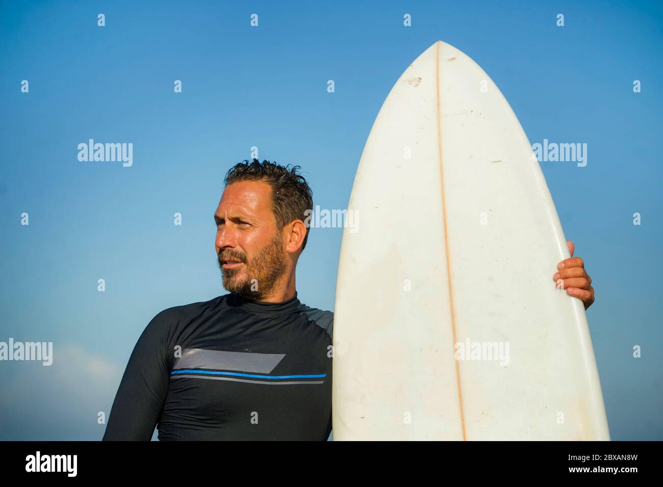 lifestyle beach portrait of handsome and attractive surfer man in ...
