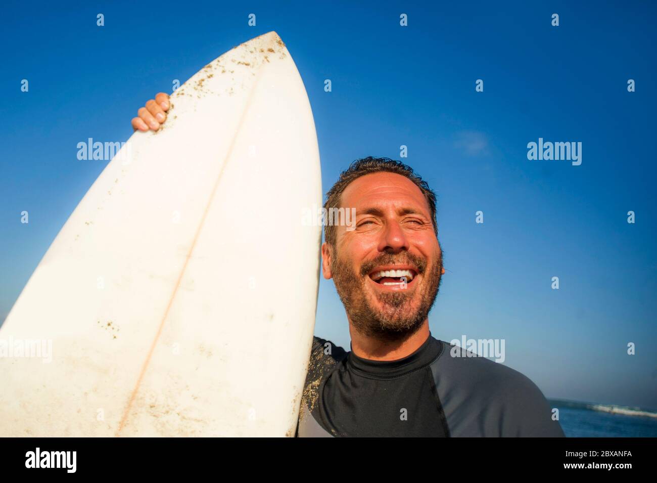 lifestyle beach closeup portrait of handsome and attractive surfer man ...