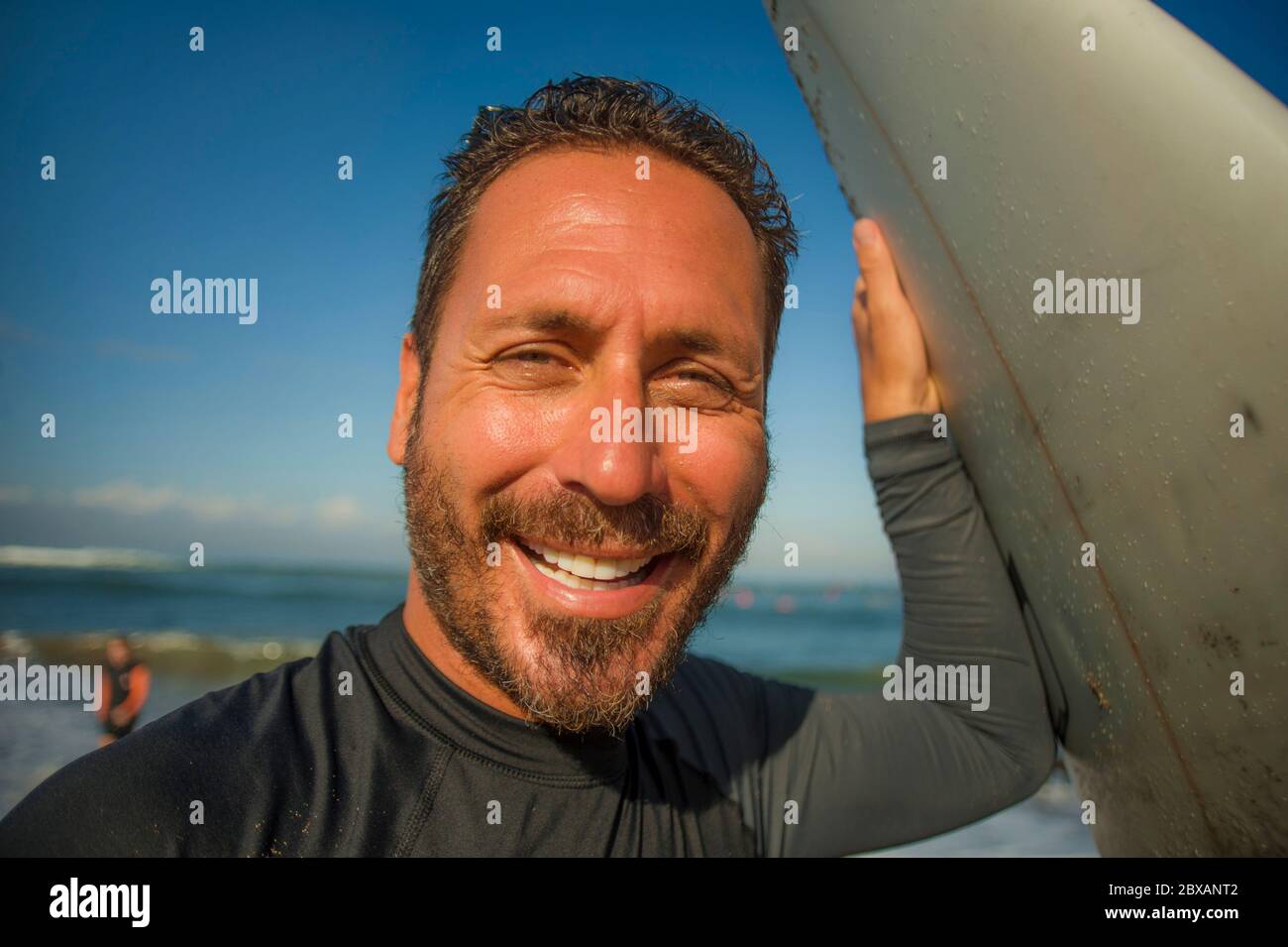 lifestyle beach closeup portrait of handsome and attractive surfer man ...