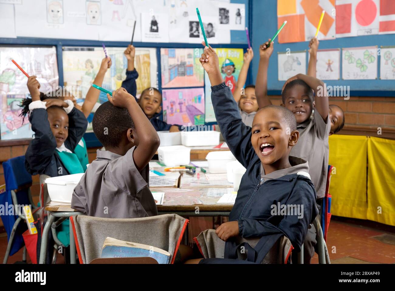 Children holding up their crayons in class Stock Photo - Alamy