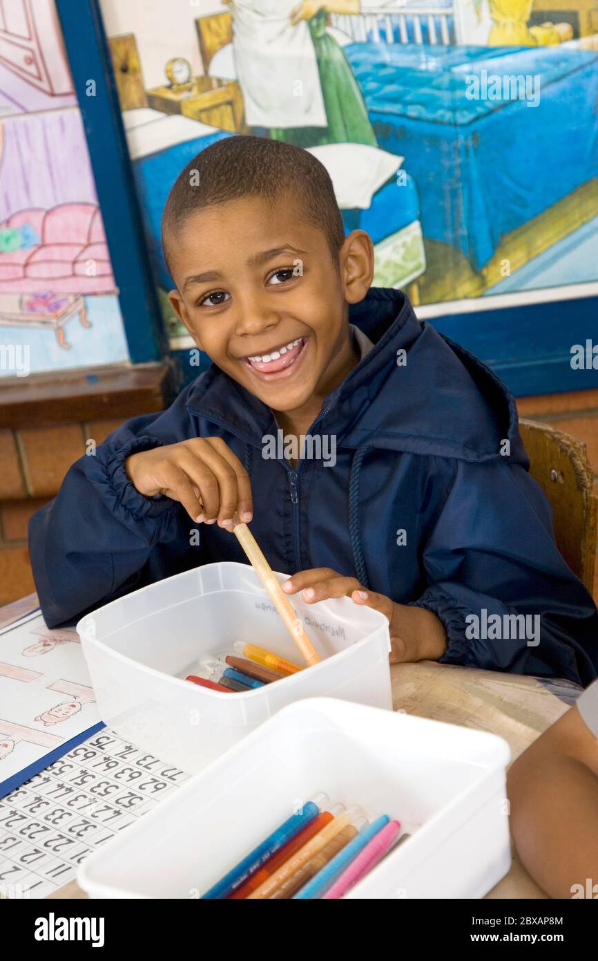 Boy with box of crayons in class Stock Photo - Alamy