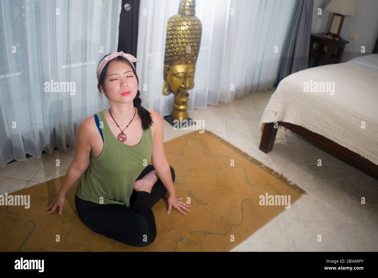 young beautiful and happy Asian Chinese woman at home doing yoga body ...