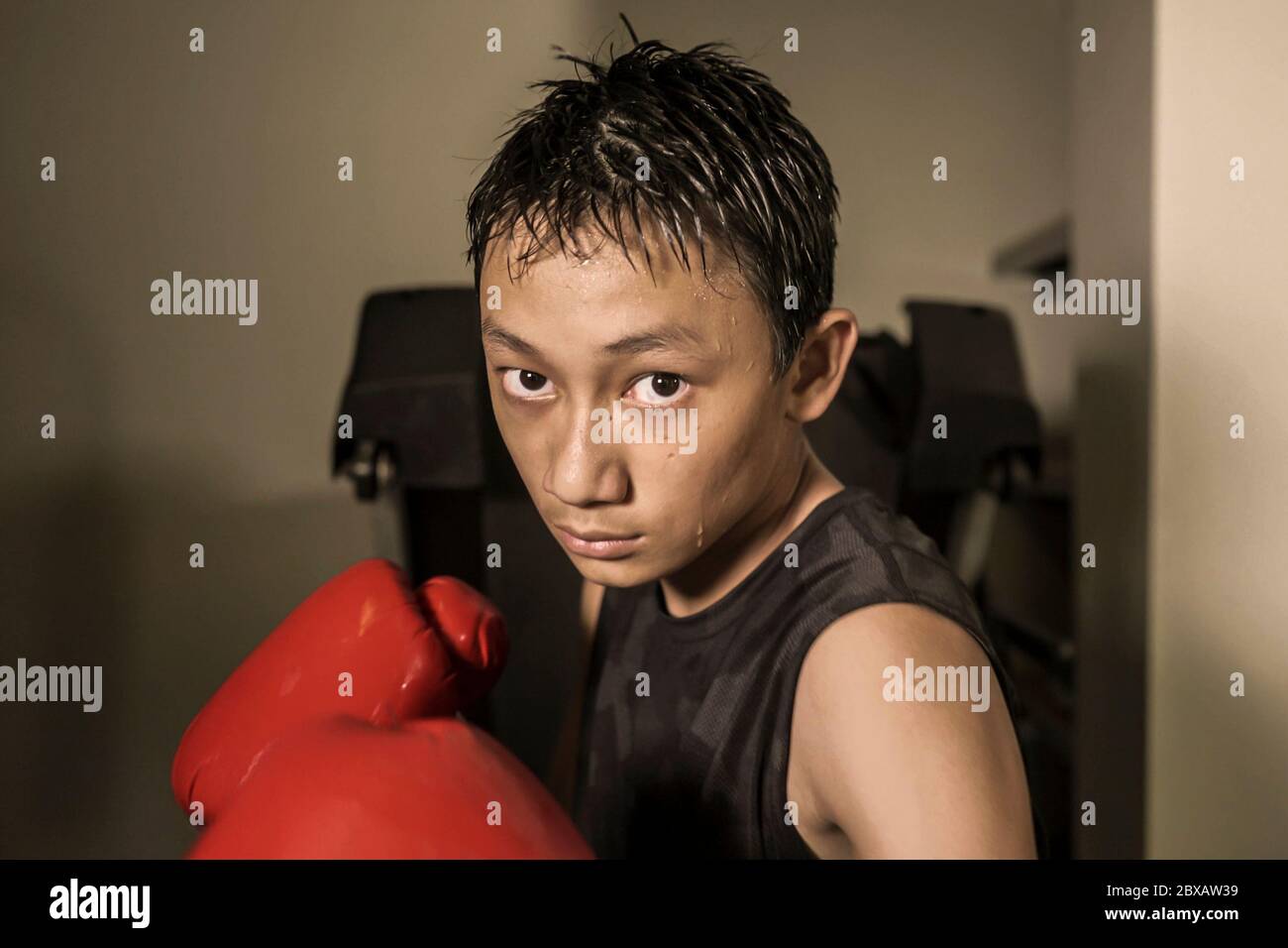 tough and cool young boy punching on heavy bag . 13 or 14 years old ...