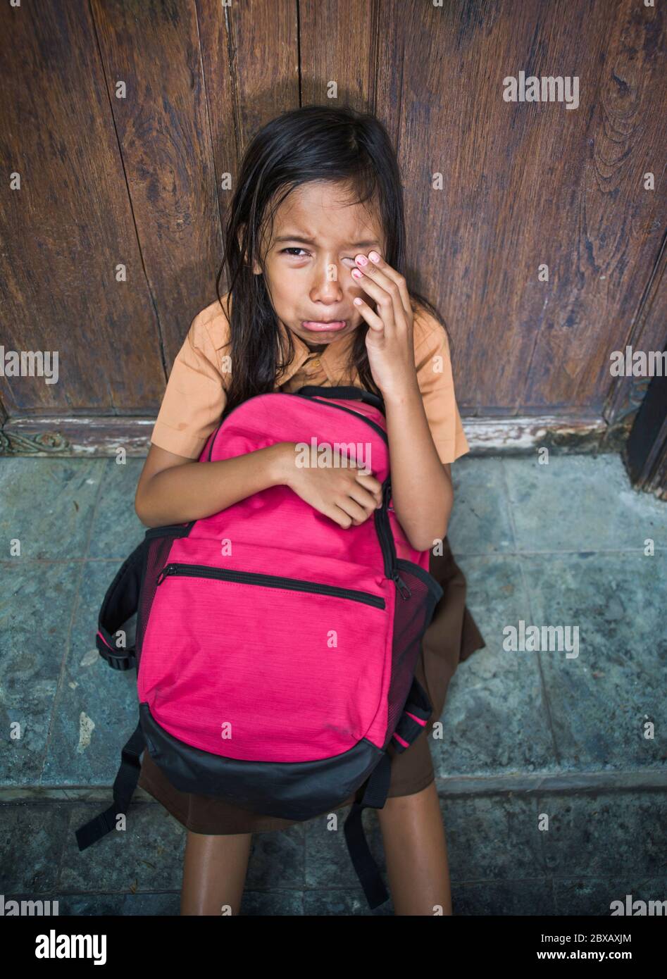 7 or 8 years child in school uniform sitting outdoors on the floor ...