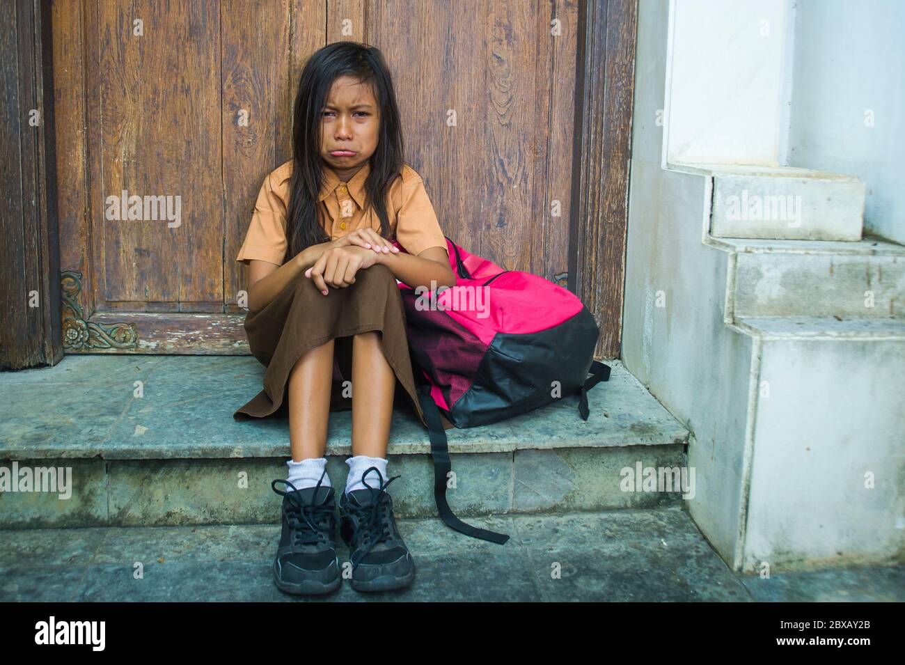 7 or 8 years child in school uniform sitting outdoors on the floor ...