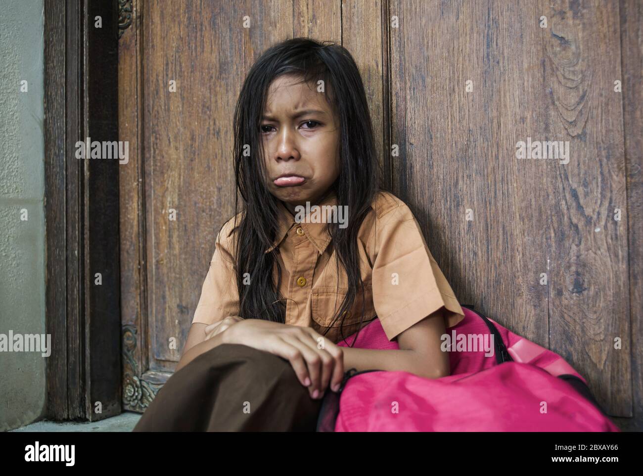 7 or 8 years child in school uniform sitting outdoors on the floor ...