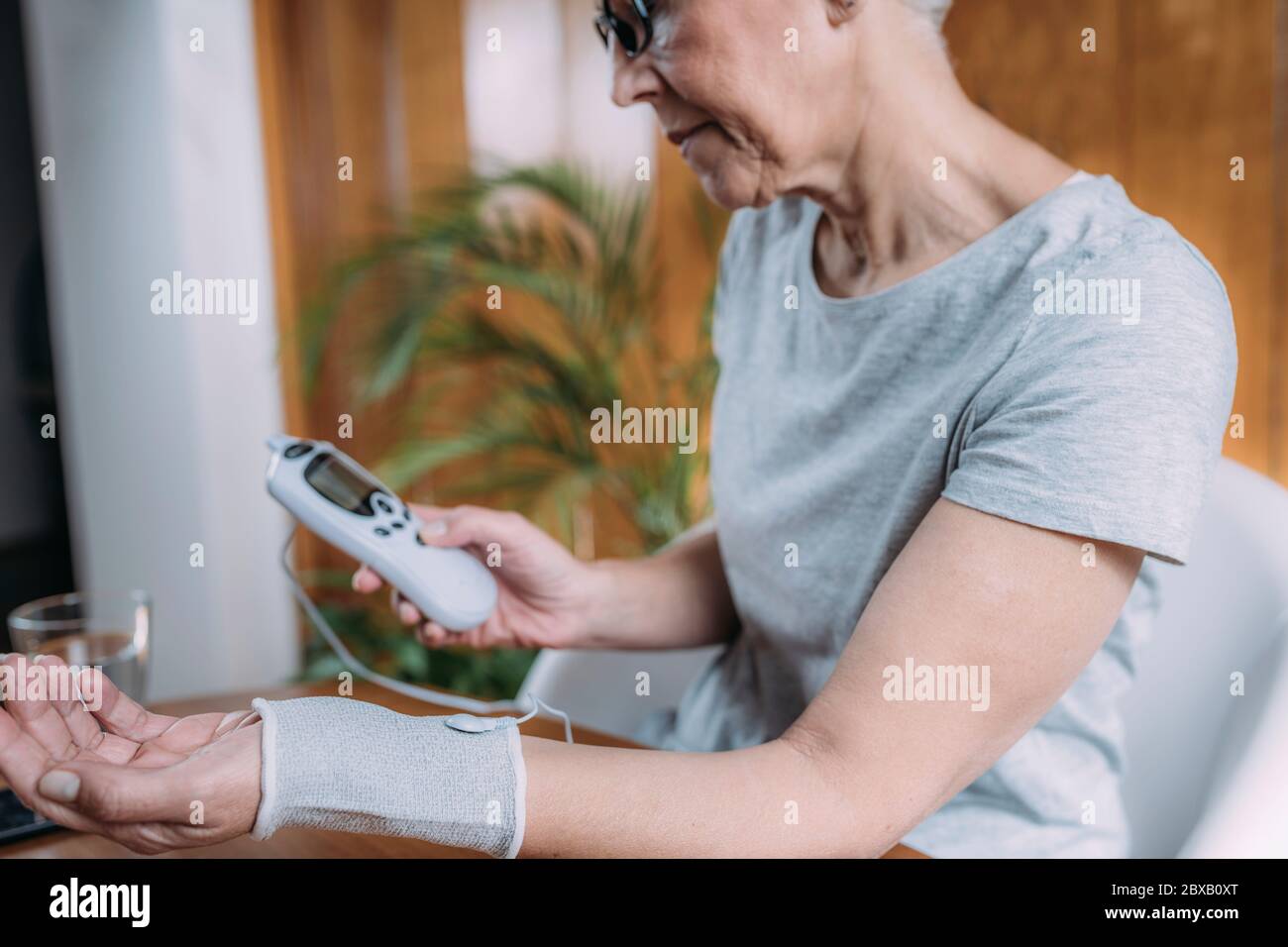 Senior woman doing wrist physical therapy with TENS Stock Photo - Alamy