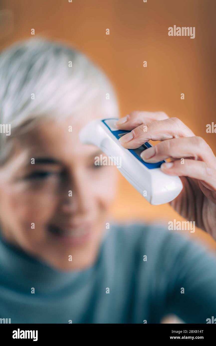 Measuring body temperature with non-contact thermometer Stock Photo - Alamy