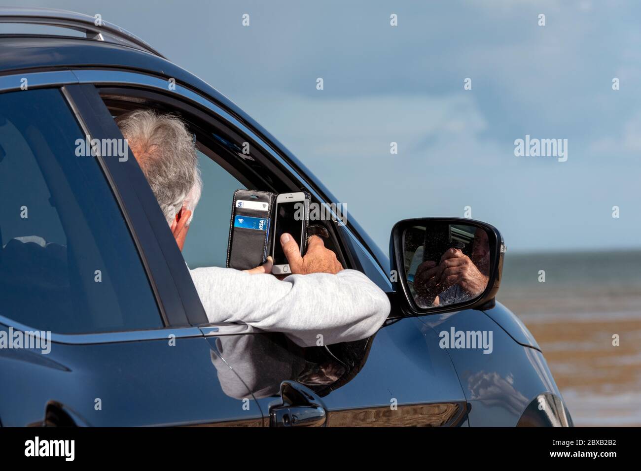 Older male using his mobile phone to take a photograph at Calshot Spit ...