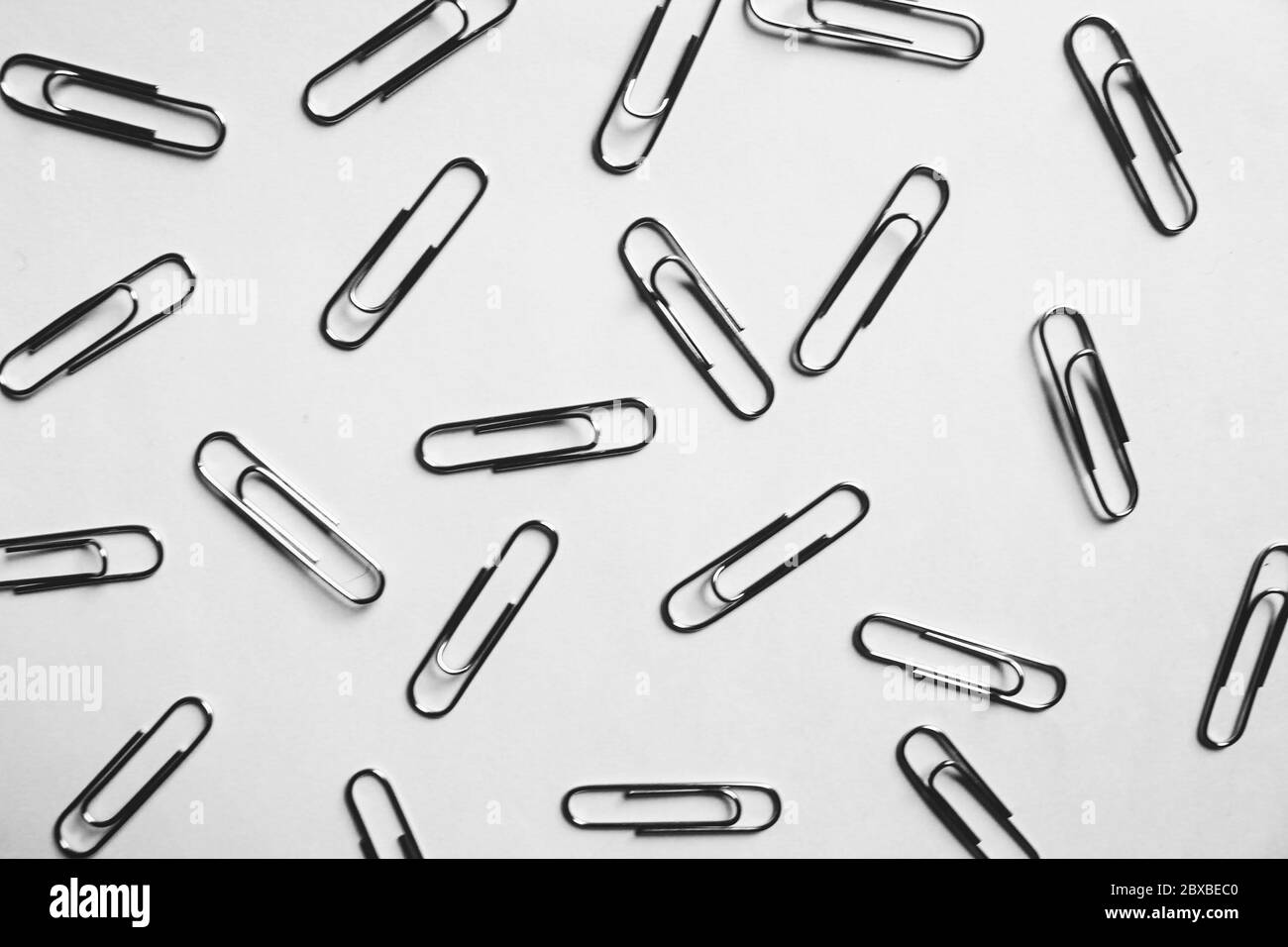 Multiple metallic paper clips spread out on a white background, offic ...