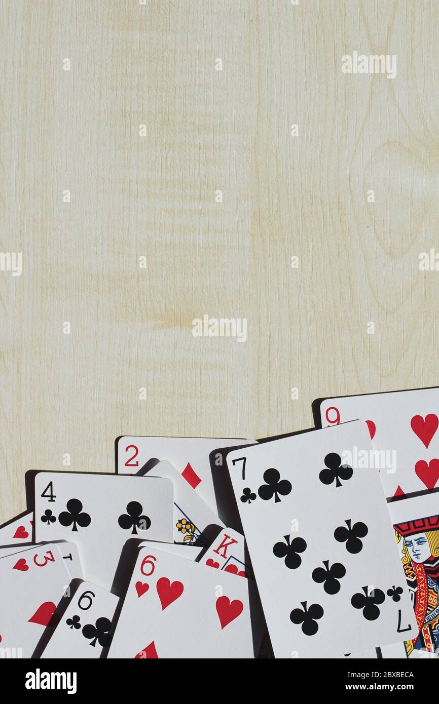 Some playing cards from a deck of cards lying on a wooden table with ...