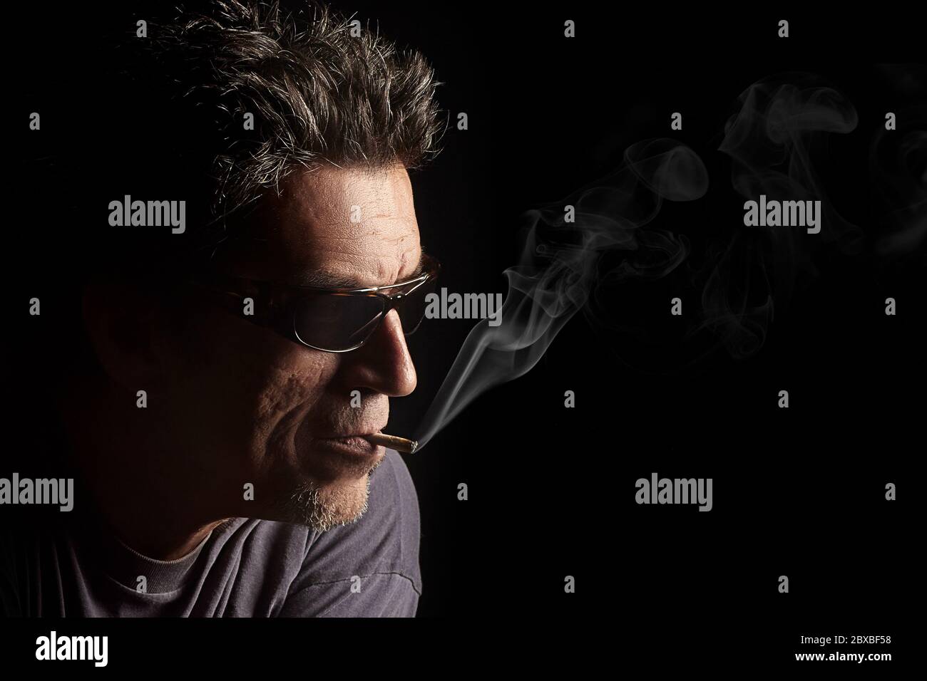 Smoking, Man with glasses and a cigar in mouth. Closeup portrait of ...