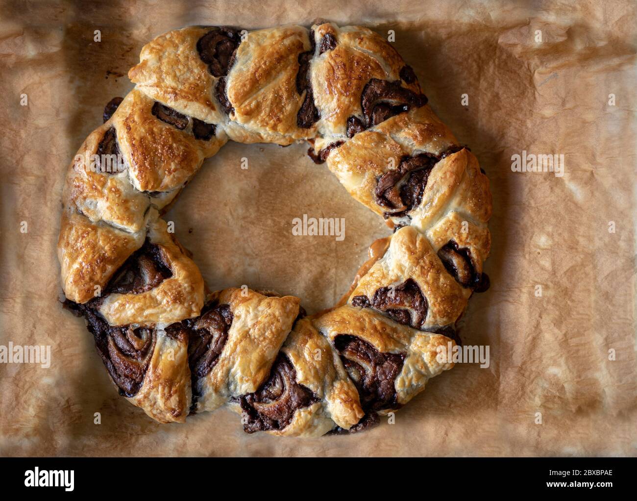 Chocolate puff pastry crown. Homemade sweet twists on a baking paper ...
