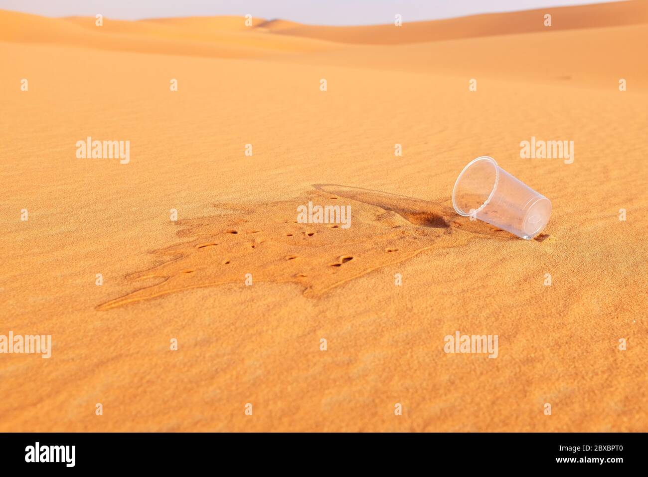 Empty glass of water in hot desert landscape. Water wastage ...
