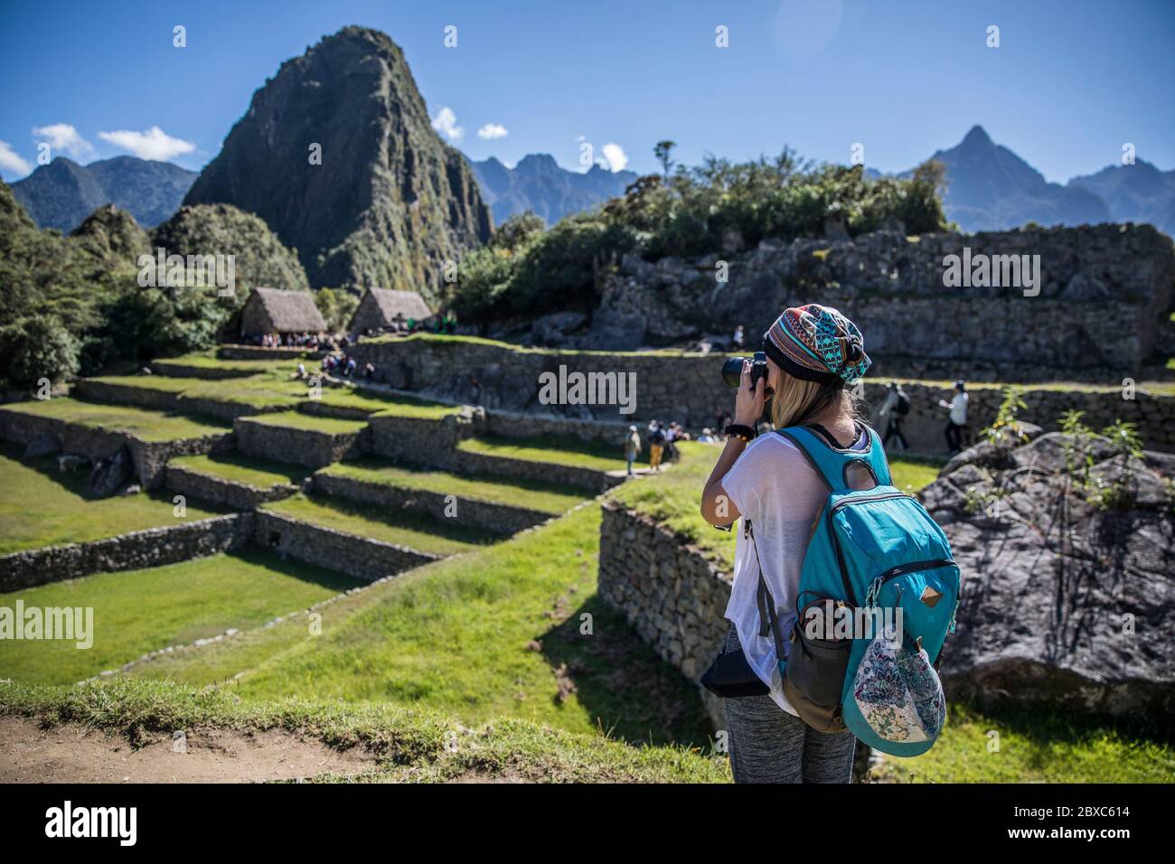 Blonde woman with camera taking pictures of machu picchu in a beautiful ...