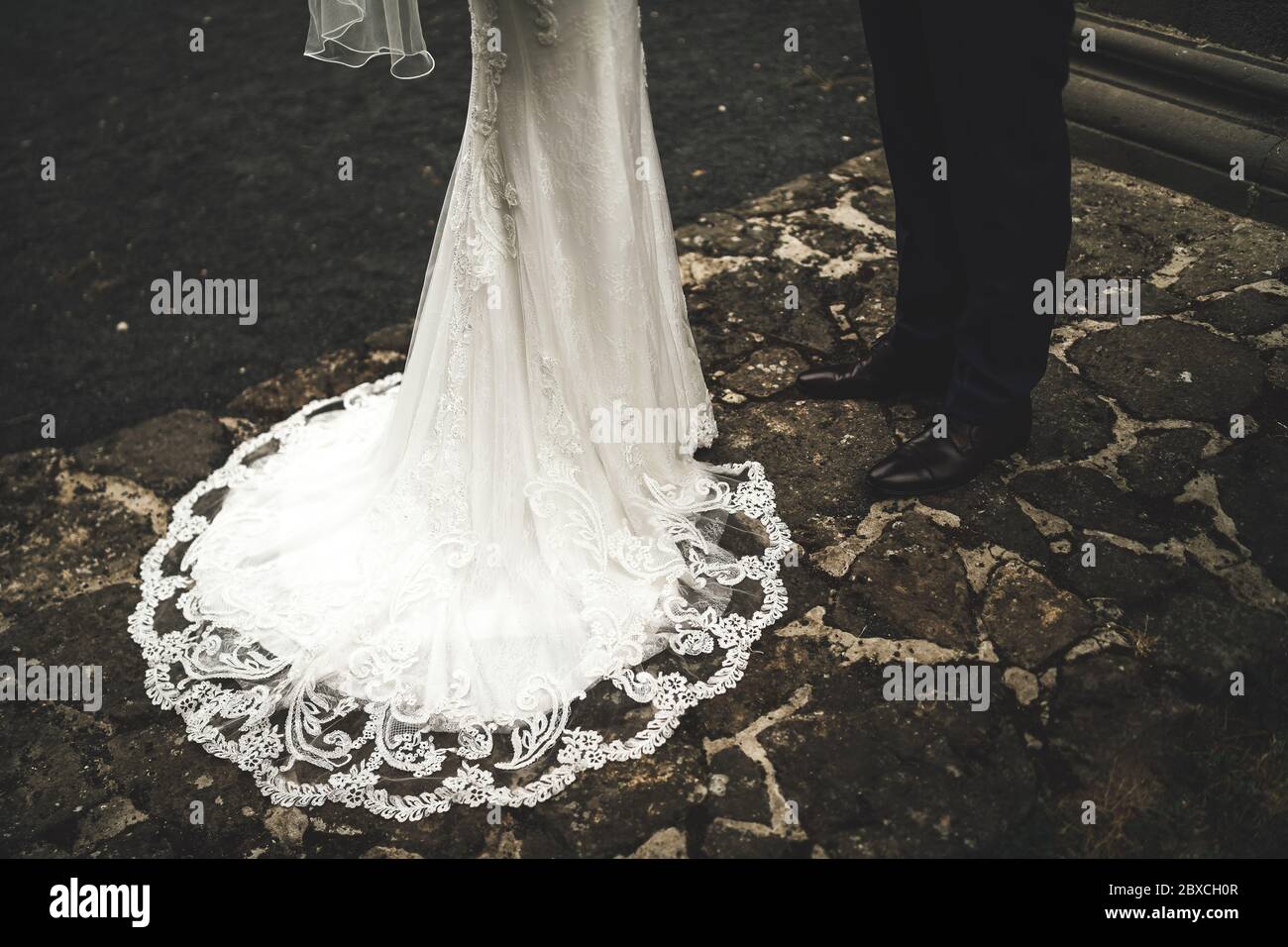 Closeup of wedding couple legs. Bride in white lace wedding gown with ...