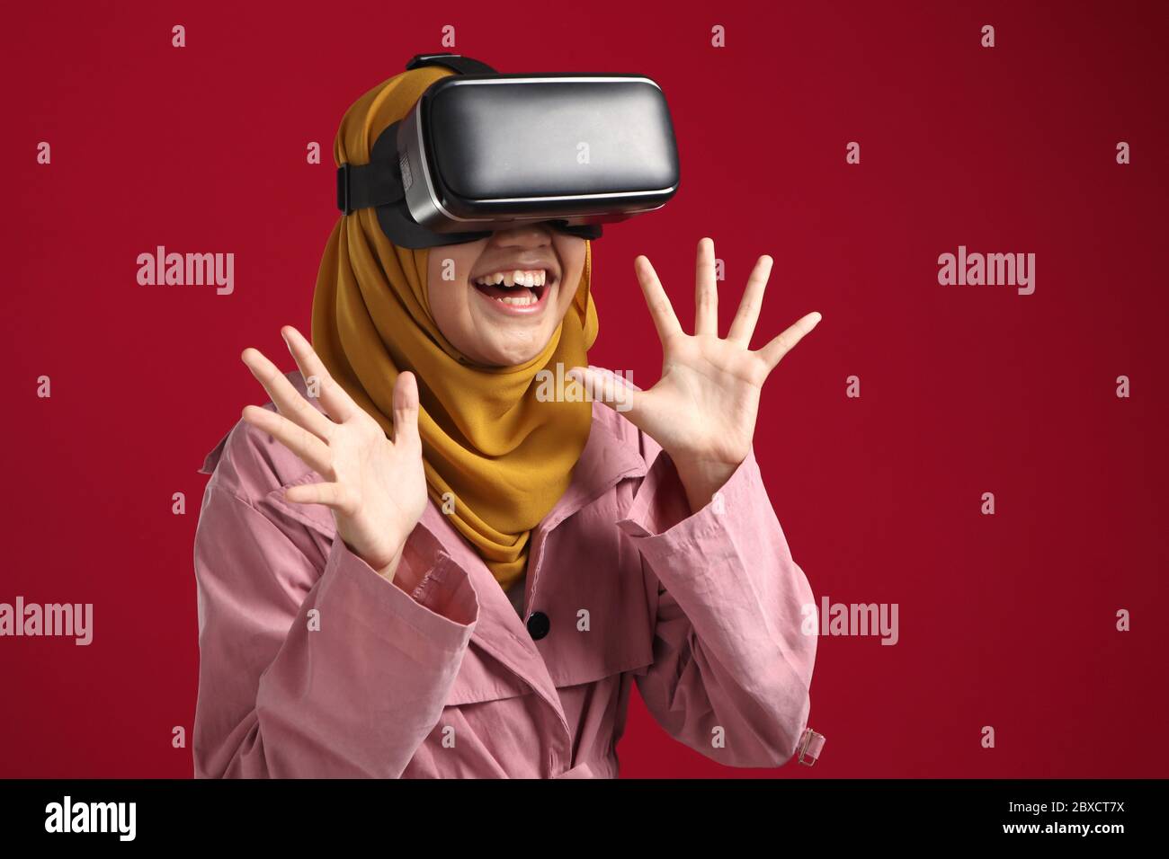 Happy young Asian muslim girl wearing hijab playing on VR glasses ...