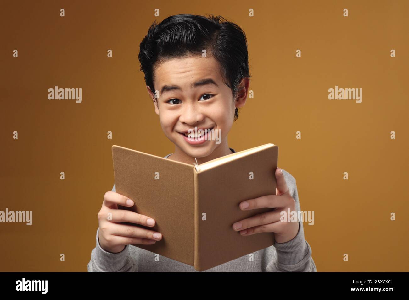 Asian boy smiling happily when reading a book, cute smart school kid ...