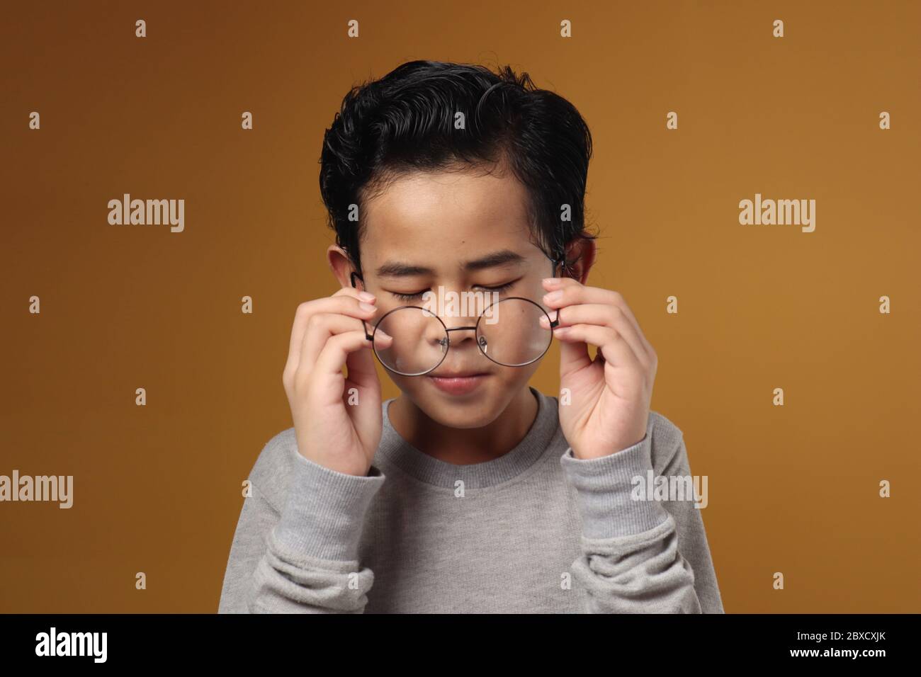 Portrait of Asian boy adjusting his eye glasses, sight problem concept ...