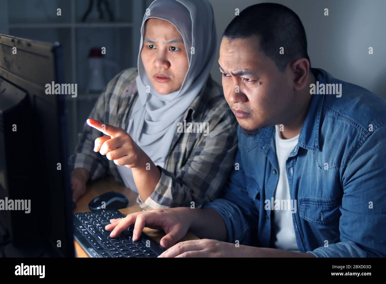 Serious muslim Asian man and woman working at night on computer ...
