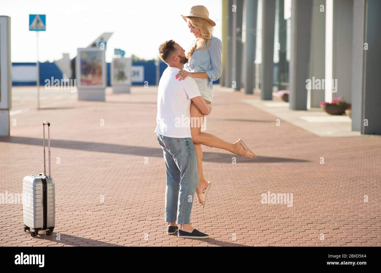 Man picking up his girlfriend near airport building Stock Photo - Alamy
