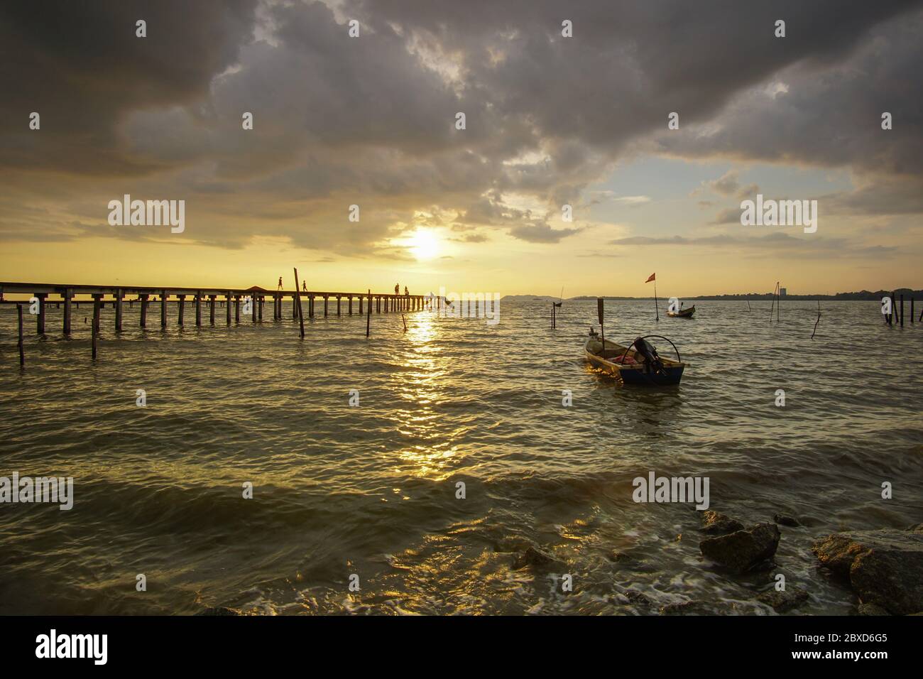 Sunset scenery at seaside over the long jetty with dramatic clouds ...
