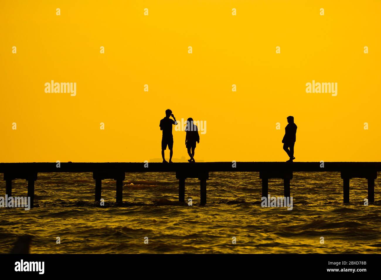 Silhouette of couples over the jetty at seascape during sunset hour Stock Photo - Alamy