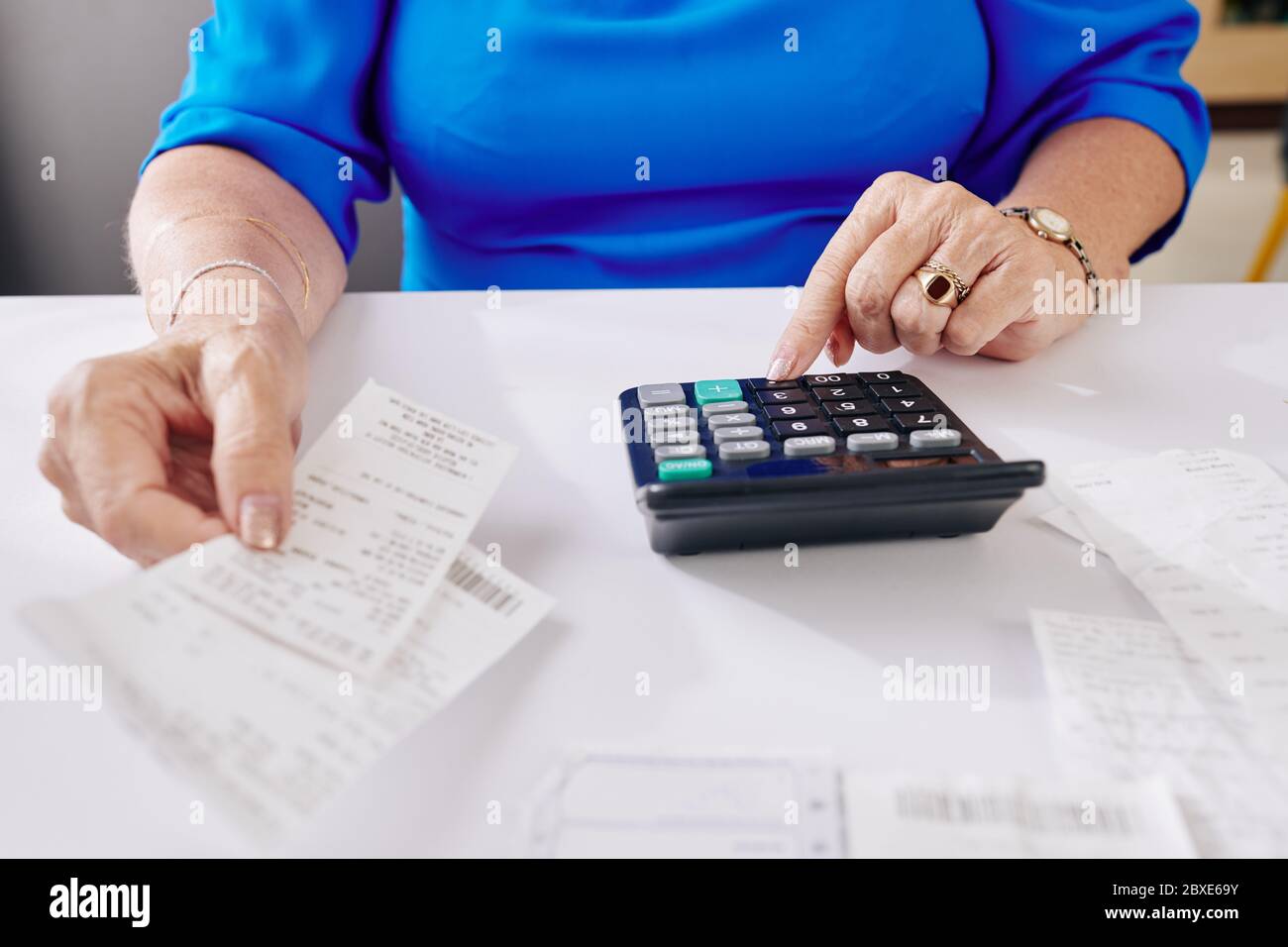 Close-up image of aged woman checking her bills and making calculations ...