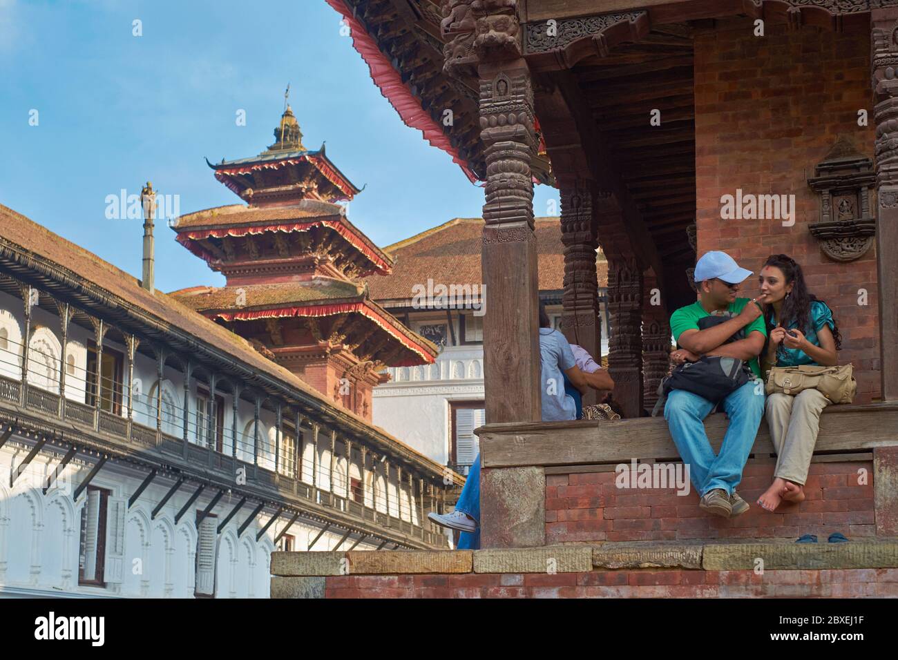 A young Nepalese couple caught in a romantic, gentle moment, while sitting in the shade of a ...