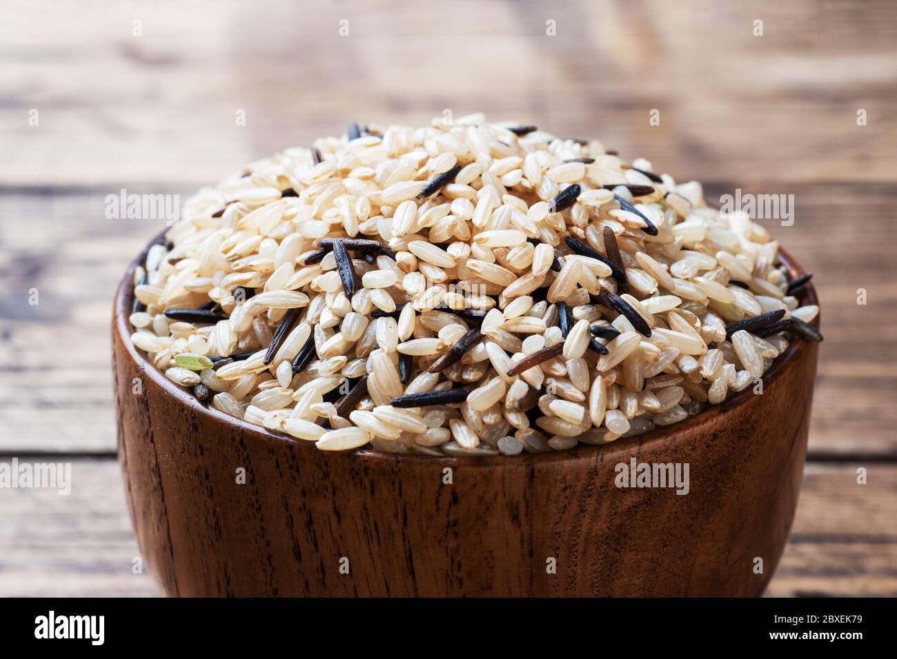 Raw wild rice in a wooden bowl. Raw rice grits on a wooden background ...