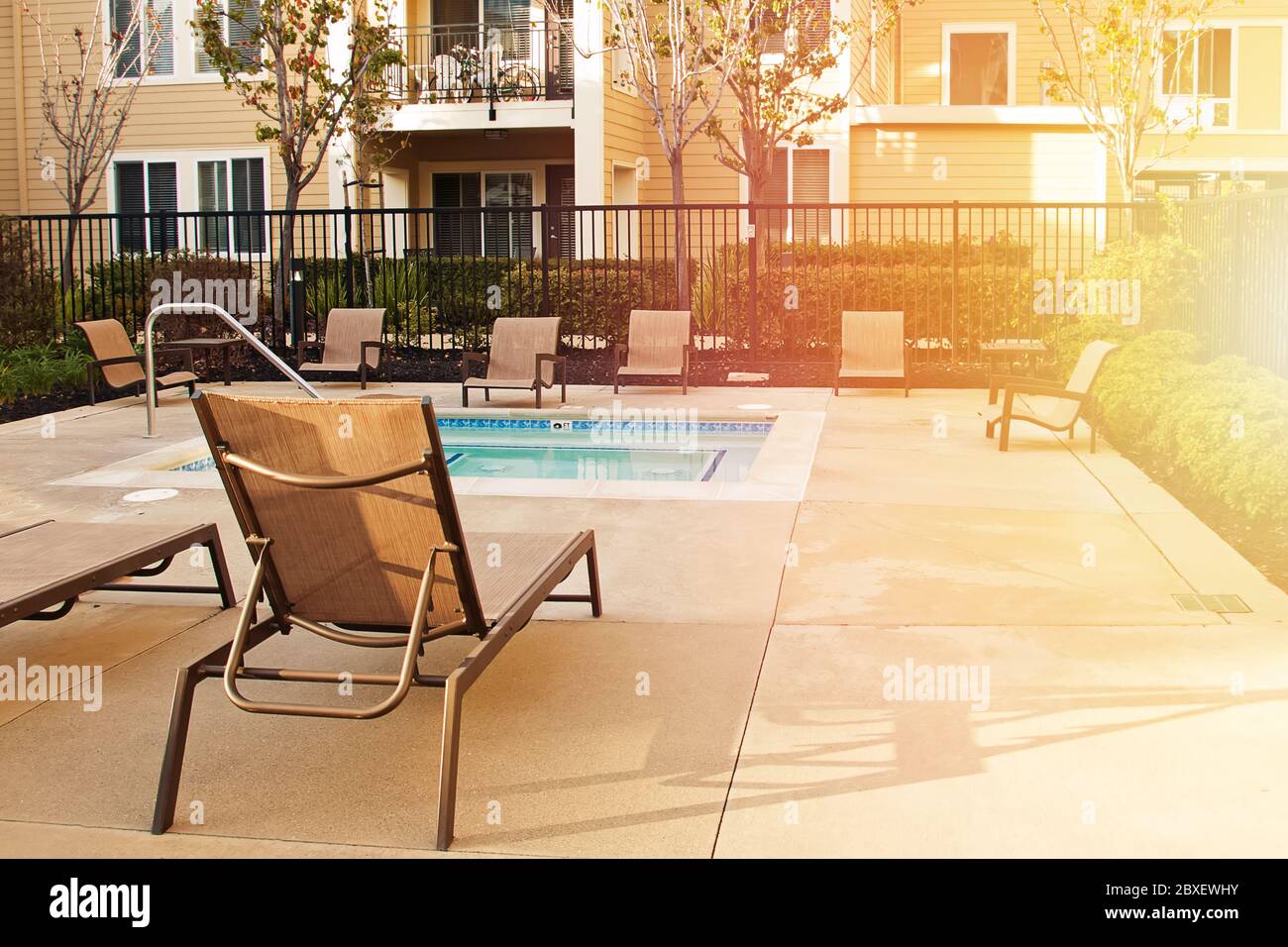 Residential pool with empty sunbed and lounge chairs in modern ...