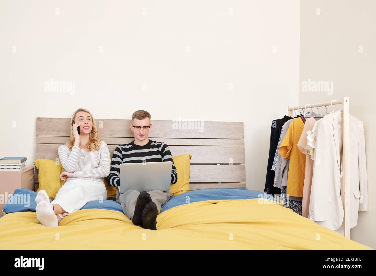 Couple staying in bed all day, man working on laptop and woman making ...