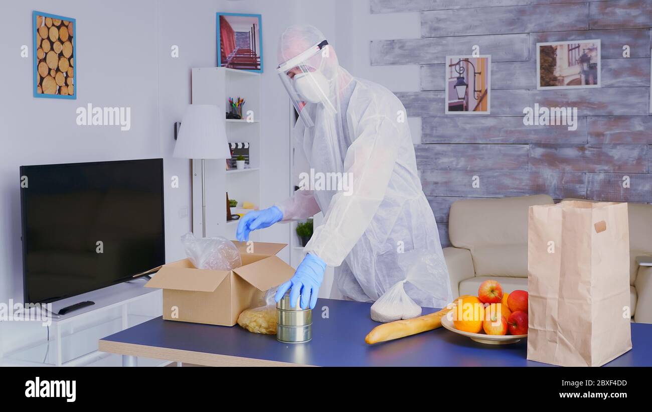 Man packing food in box for delivery wearing protective suit against ...
