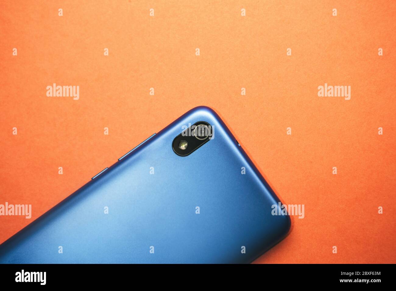 Rear view cell or mobile phone with a camera on a orange background ...