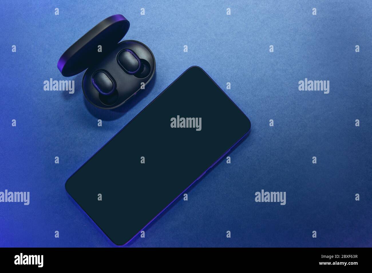The wireless headphones in the box are unpacked and the cell phone on a ...