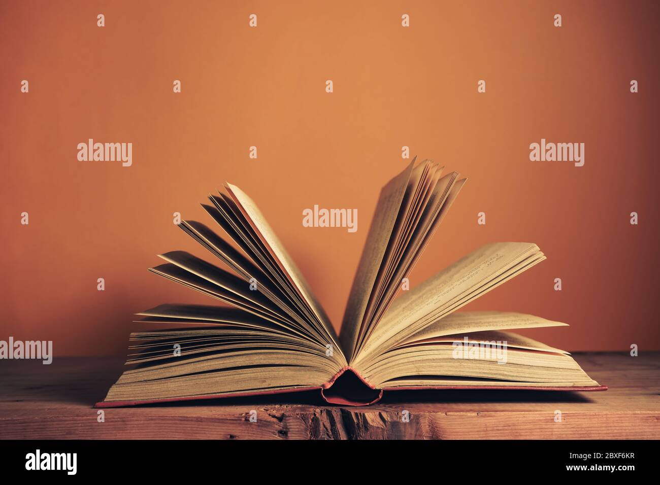 Beautiful ancient open old book on a red wooden table and orange wall ...