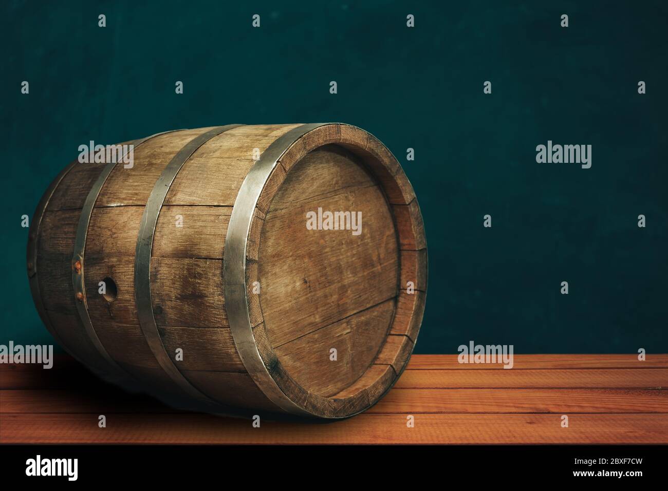 Beautiful wooden barrel on a red wood table and green wall background ...
