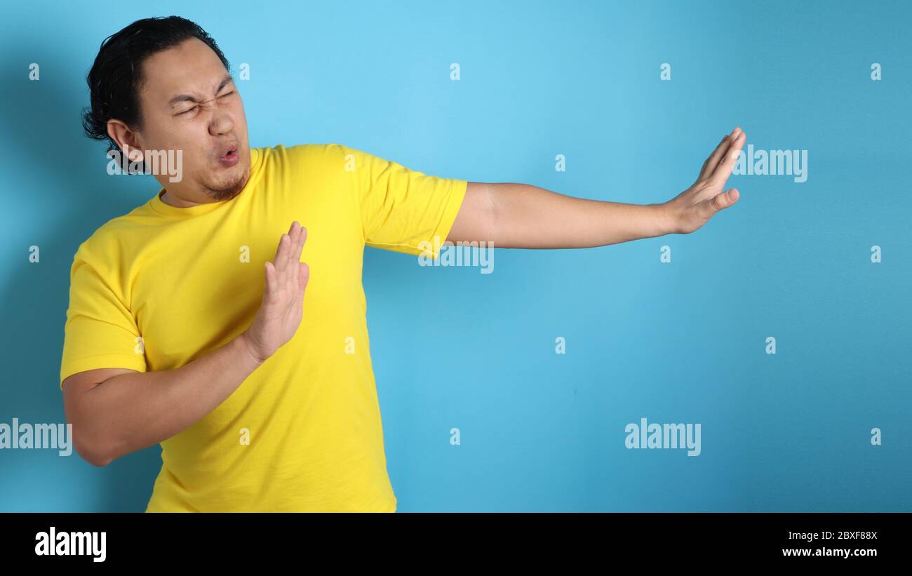 Portrait of young funny Asian man avoiding as if he is worried afraid ...