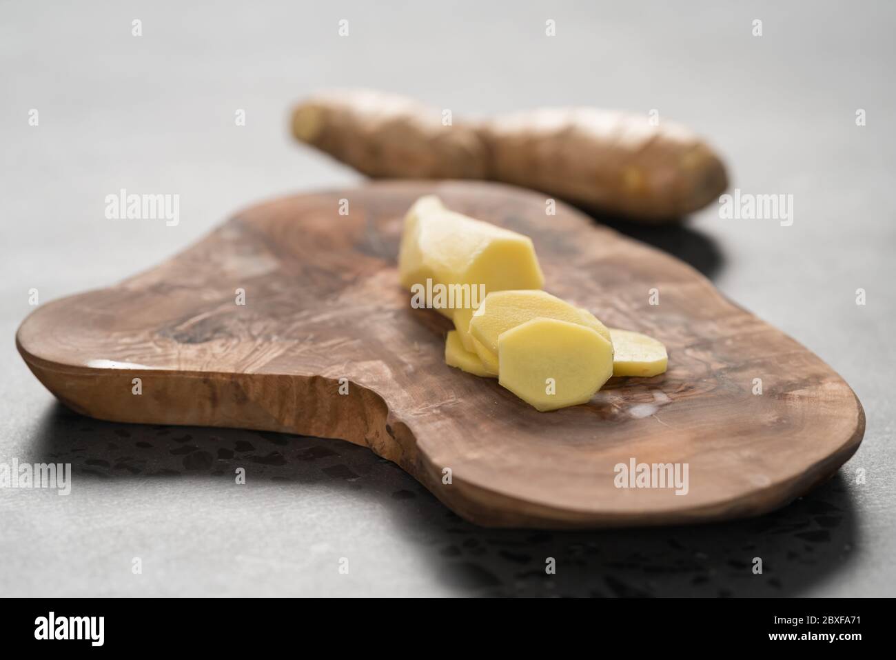 Sliced fresh ginger root on olive wood board Stock Photo - Alamy