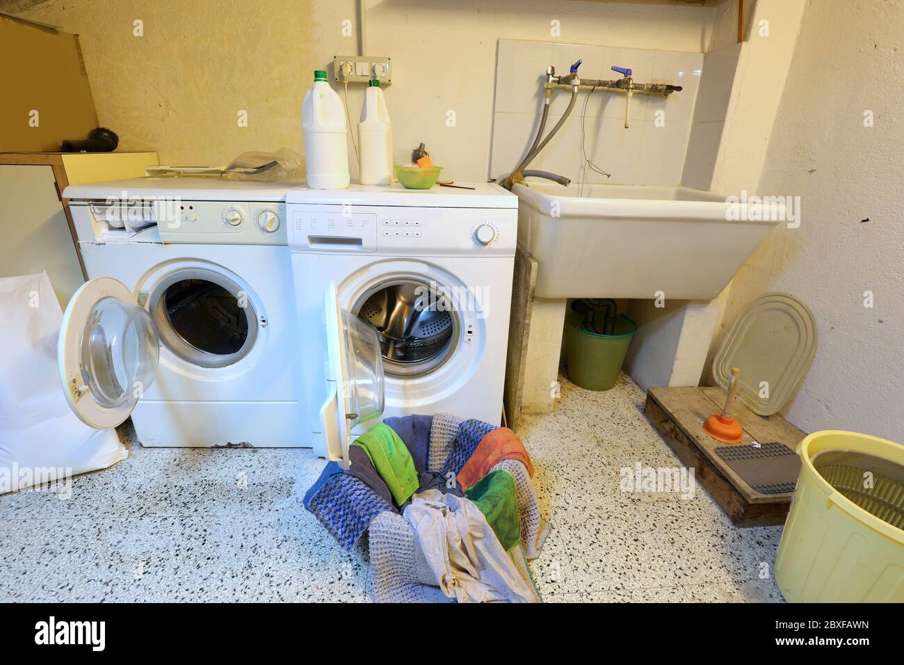 interior of a laundry area with two washing machines and clothes to ...