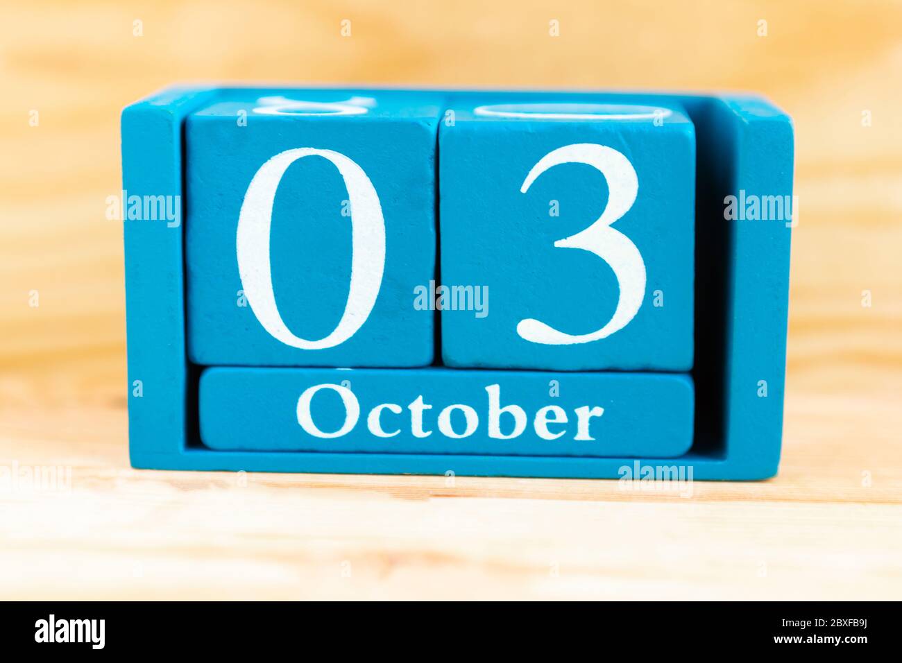 October third. Blue cube calendar with month and date on wooden ...