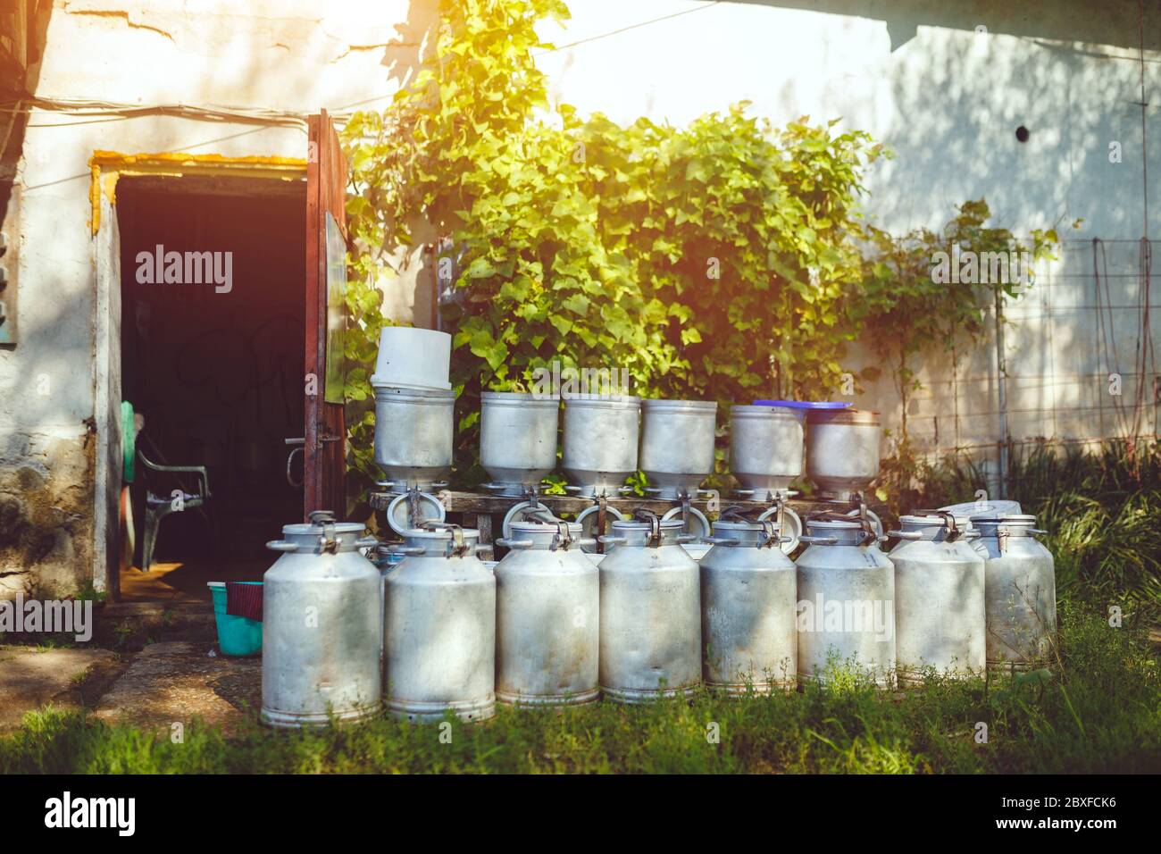 Vintage milk cans standing oustside the barn in rural countryside farm ...