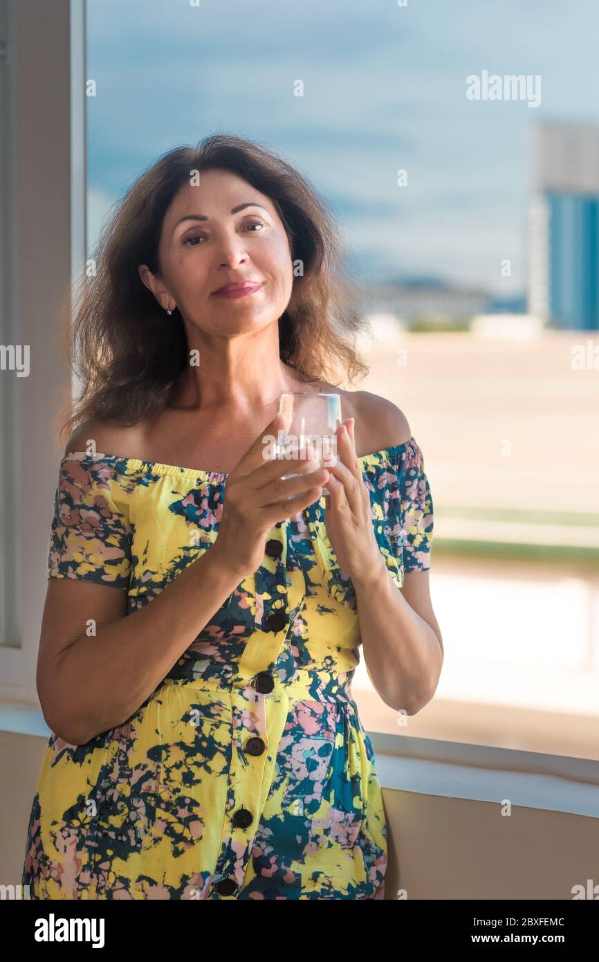 Indoor portrait of a beautiful smiling senior woman next to window ...